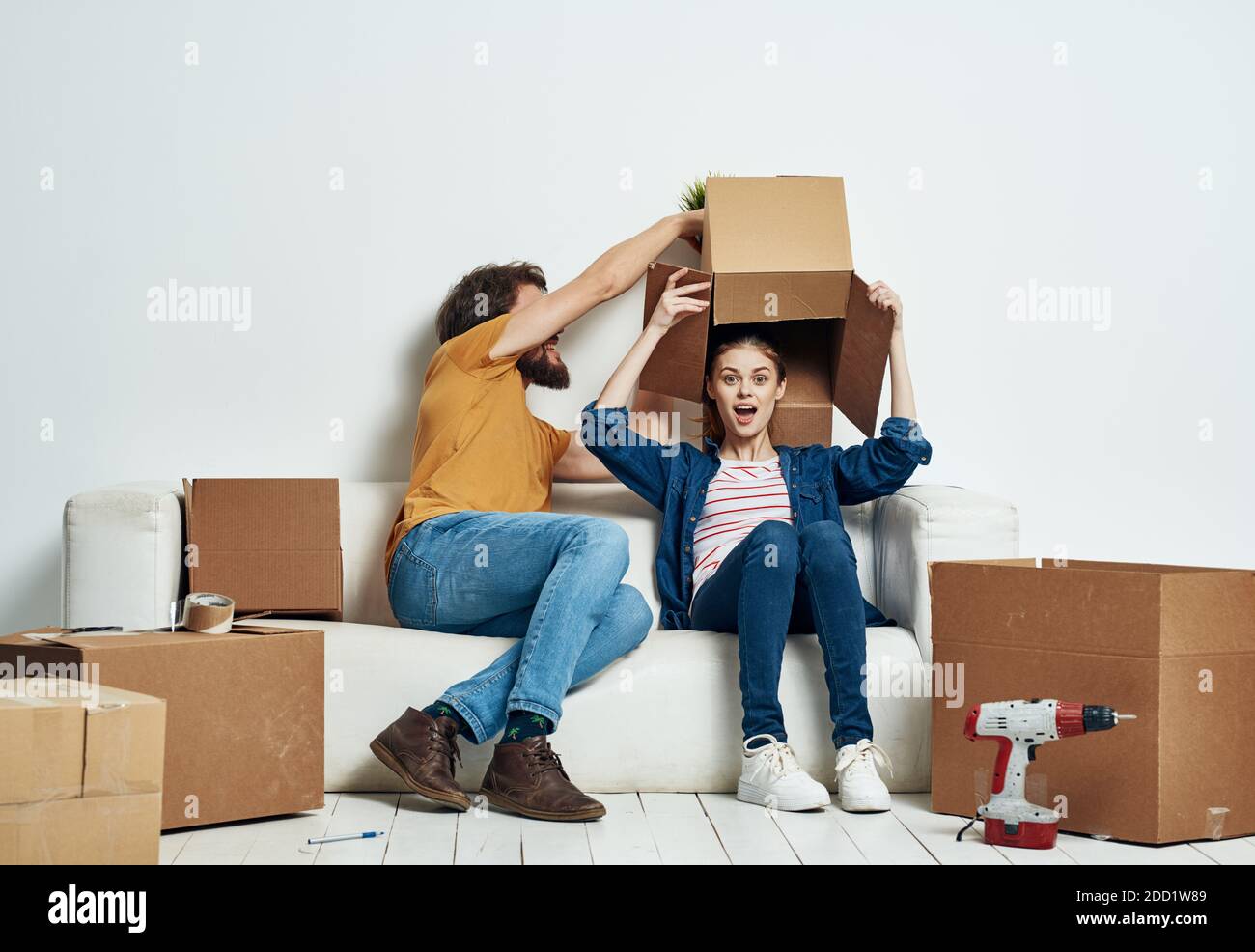 Man and woman sit on white couch boxes with moving lifestyle things ...