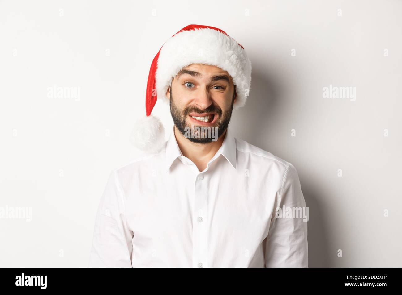 Close-up of awkward guy in santa hat apologizing, feeling uncomfortable ...