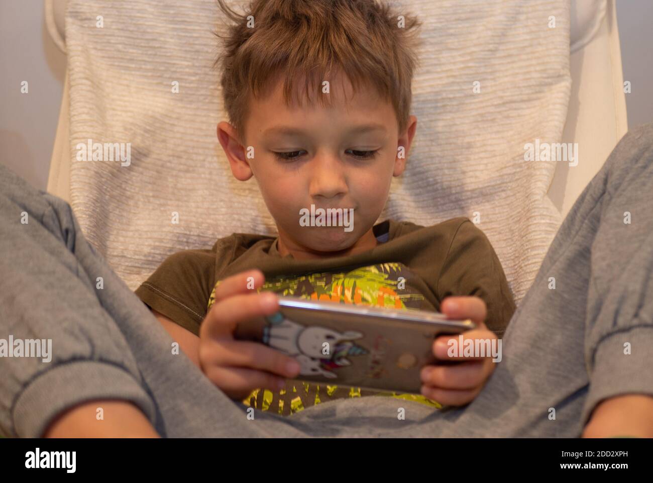 boy playing on the phone sitting in a chair Stock Photo - Alamy