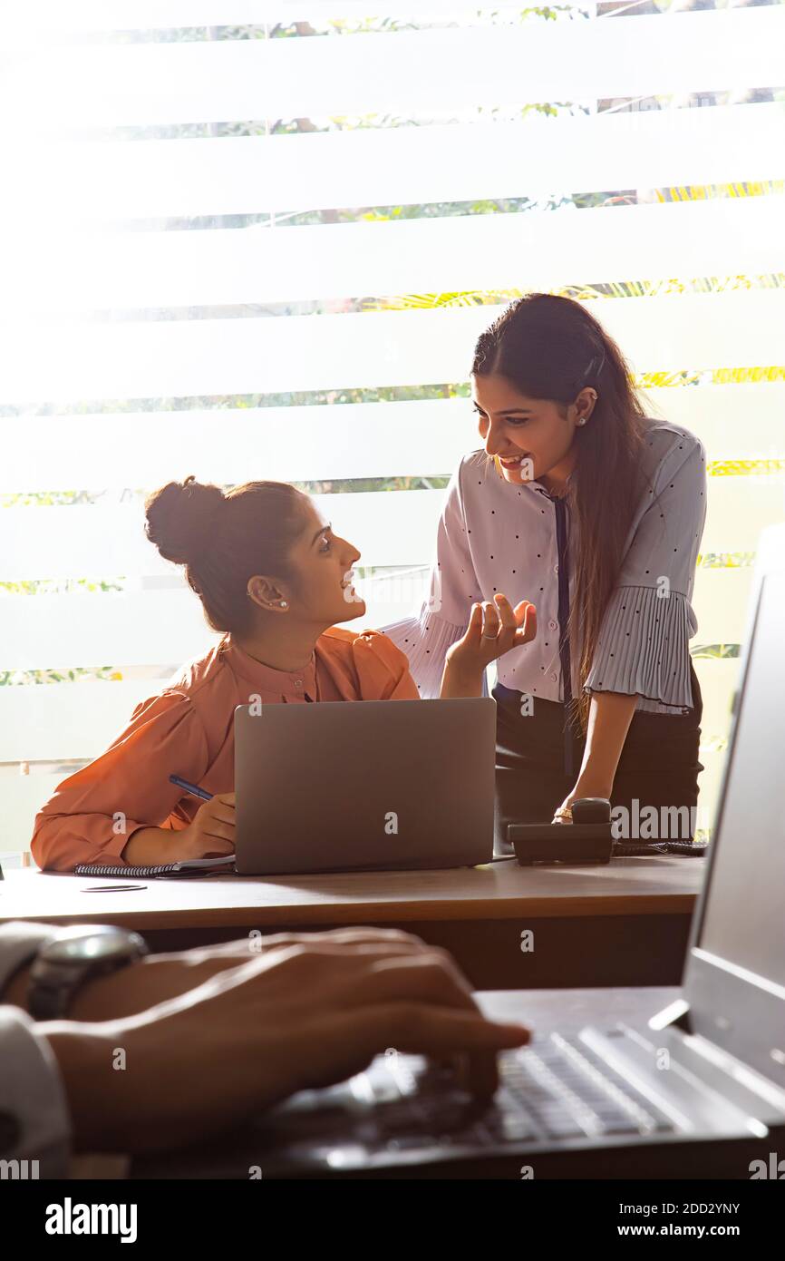 TWO WOMEN EXECUTIVES HAPPILY DISCUSSING WORK DURING OFFICE TIME Stock ...