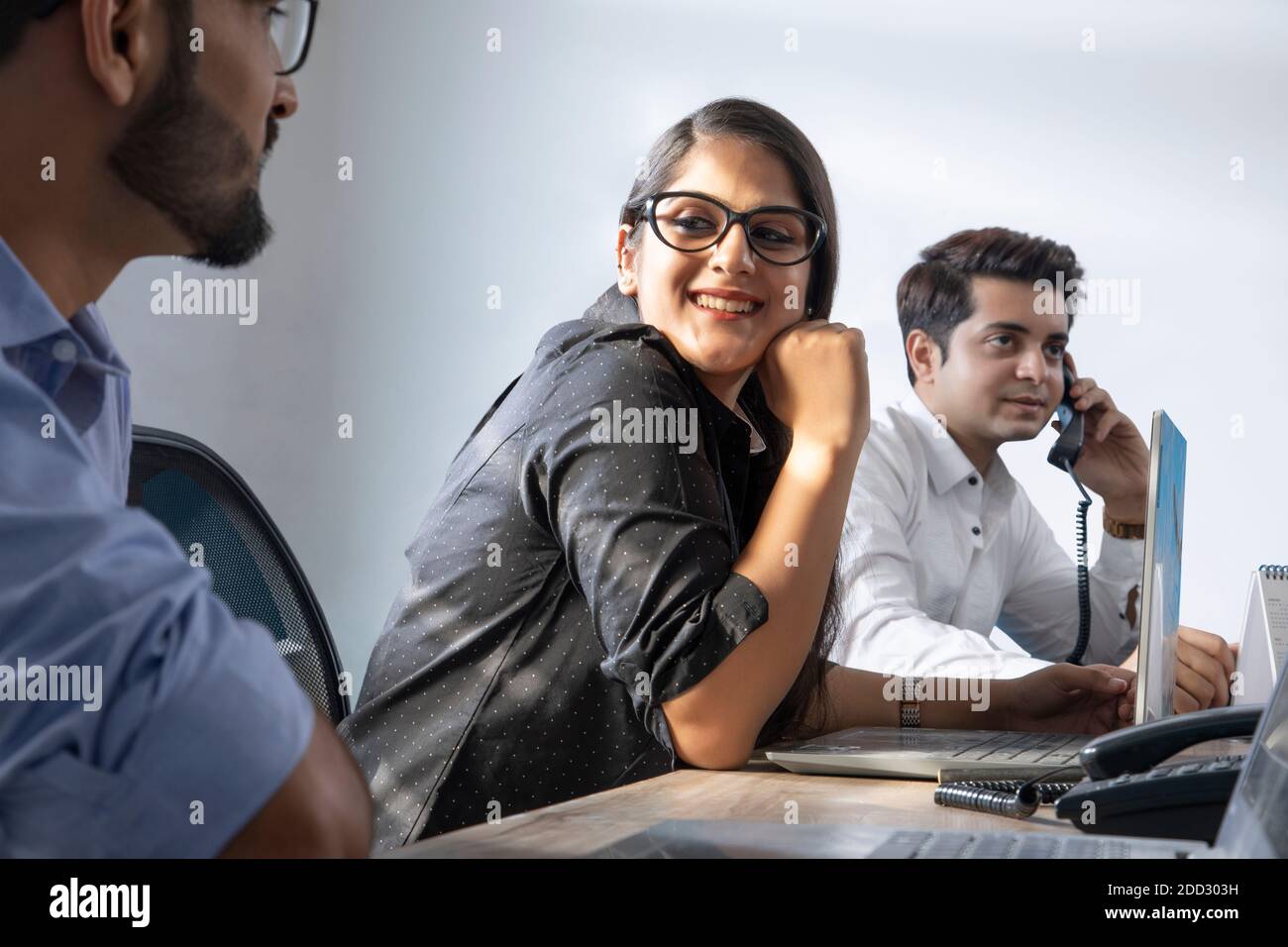 A YOUNG WOMAN HAPPILY TALKING TO COLLEAGUE WHILE WORKING Stock Photo ...