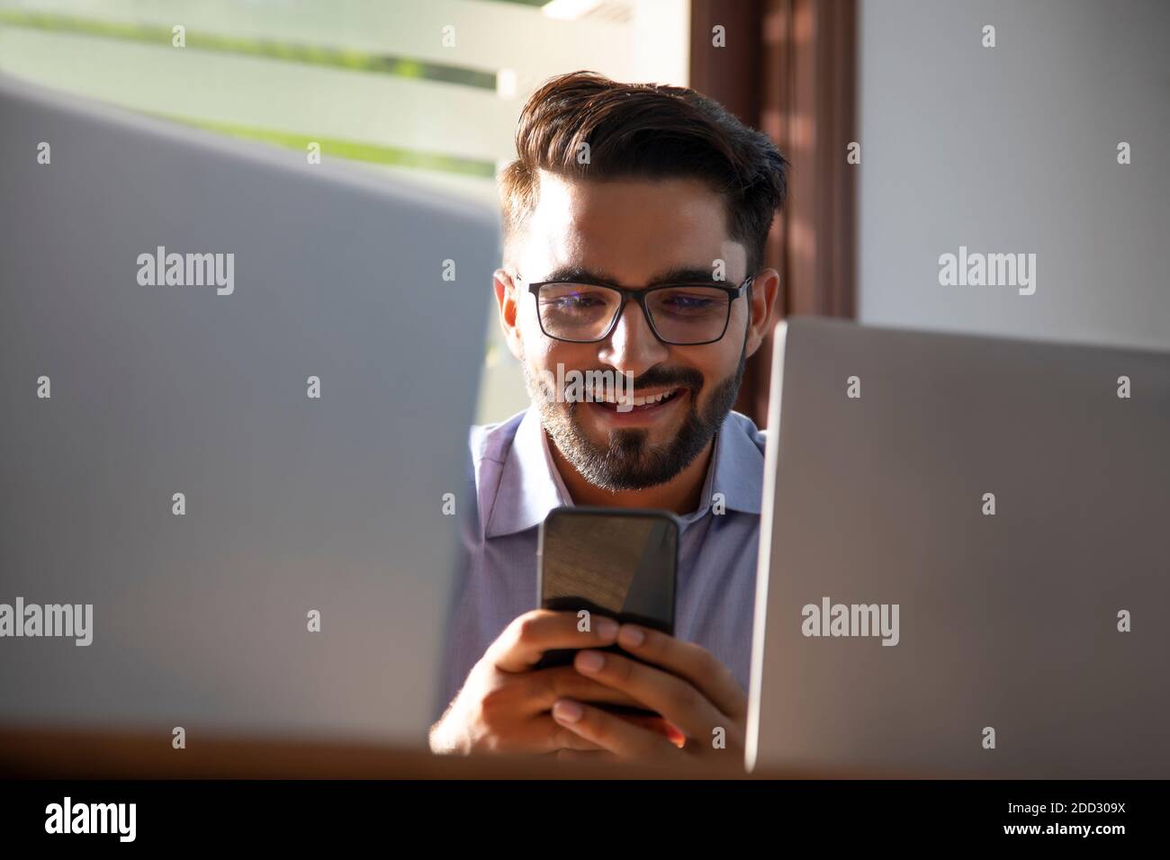 A YOUNG MAN HAPPILY USING MOBILE PHONE DURING WORK Stock Photo - Alamy