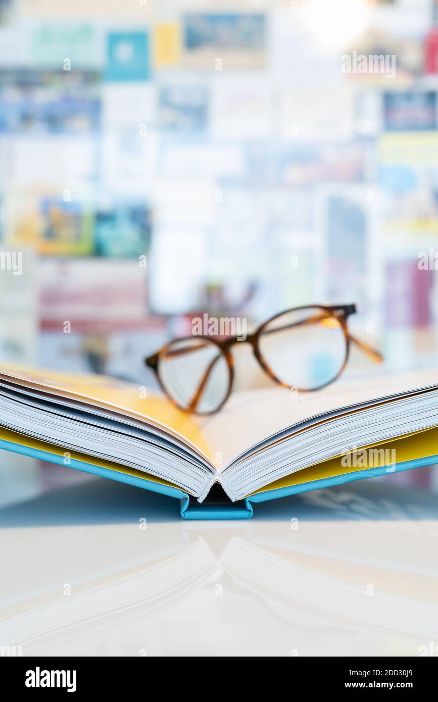 Open book lying on white table with soft blurred reading glasses in ...