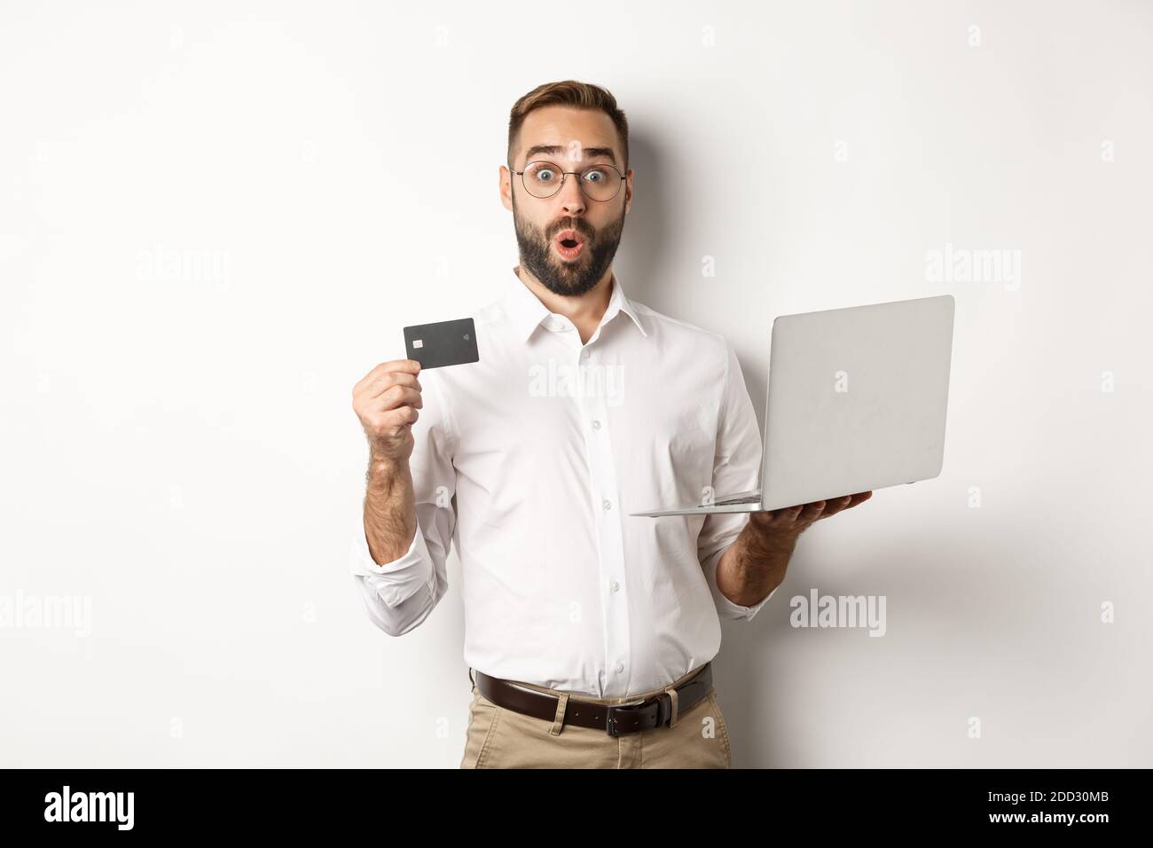 Online shopping. Surprised man holding laptop and credit card, shop ...