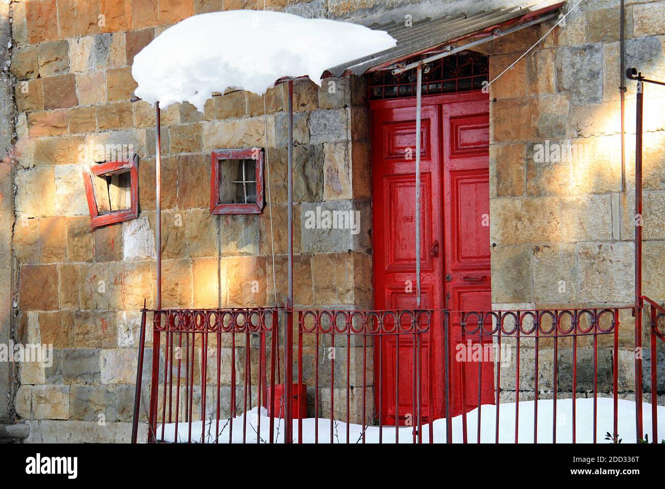 A rustic house in the village of Hasroun with a red door and snow ...