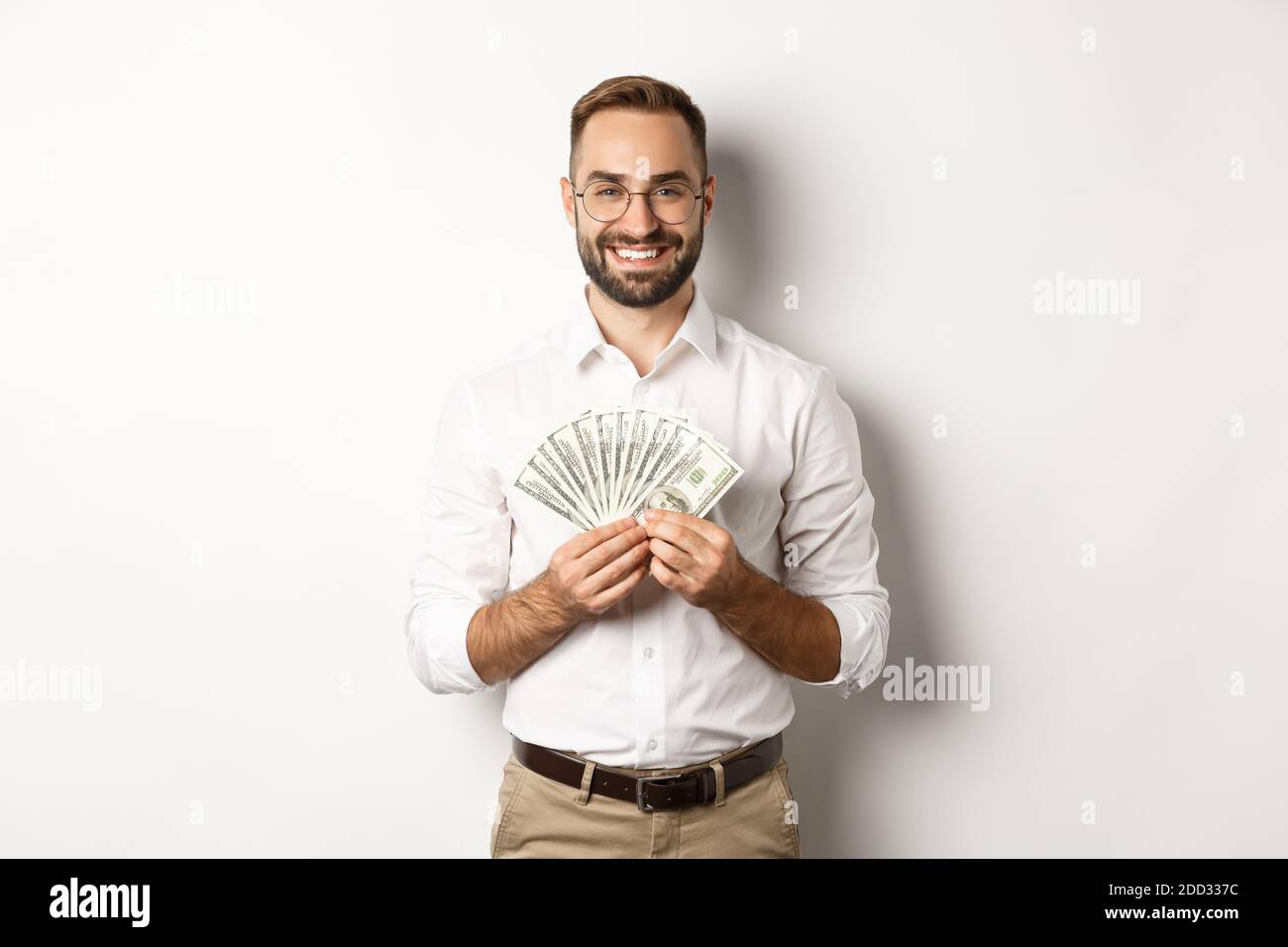 Smiling handsome man holding money, showing dollars, standing over ...