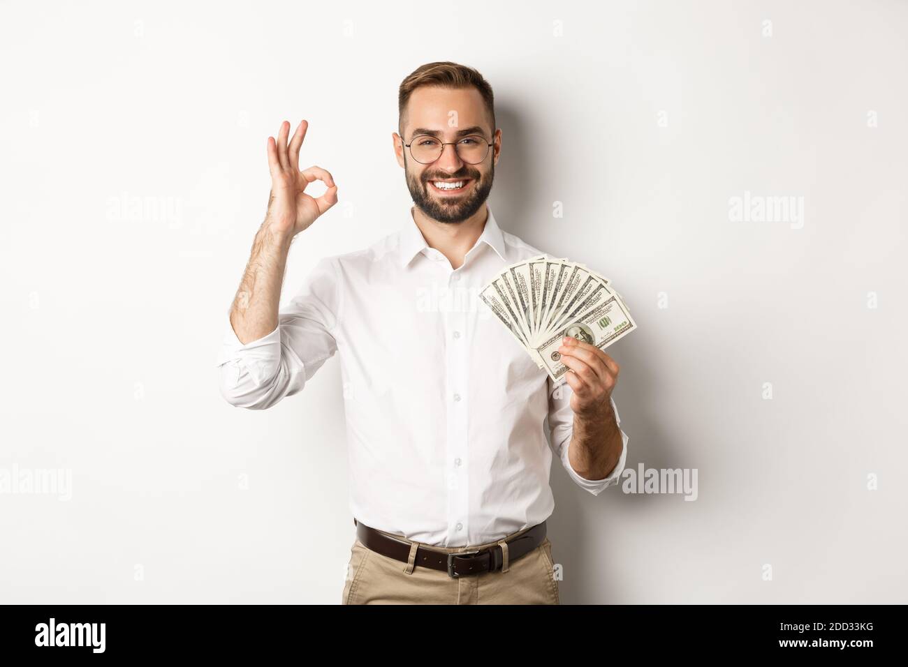 Satisfied young businessman showing money, make okay sign, earning cash ...