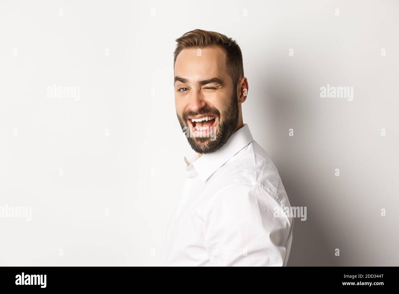 Close-up of cheeky guy with beard, turn face at camera and winking with ...