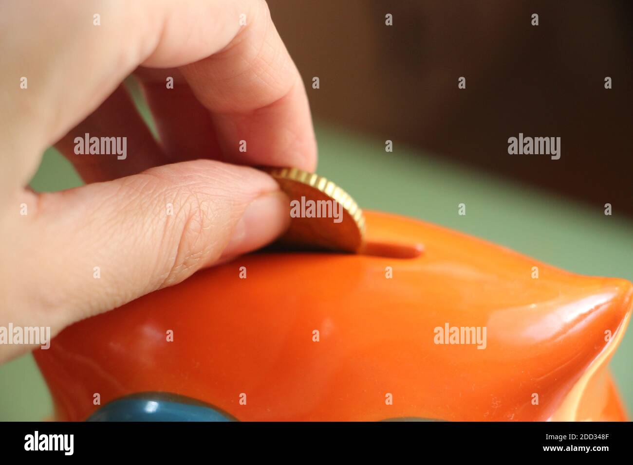 Hand puts coin in orange saving moneybox. Money saving and investment ...