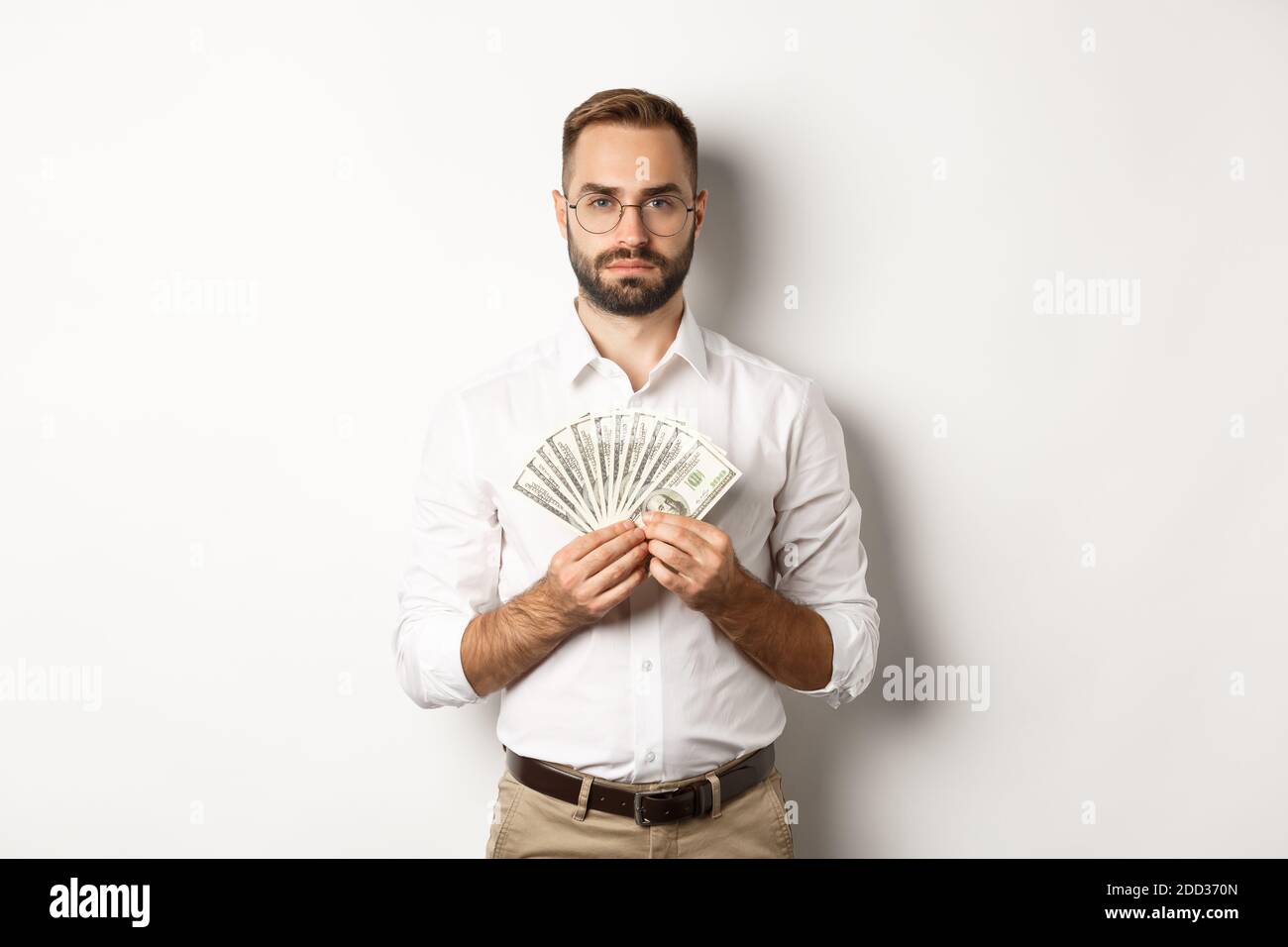 Serious businessman holding money, showing dollars, standing over white ...