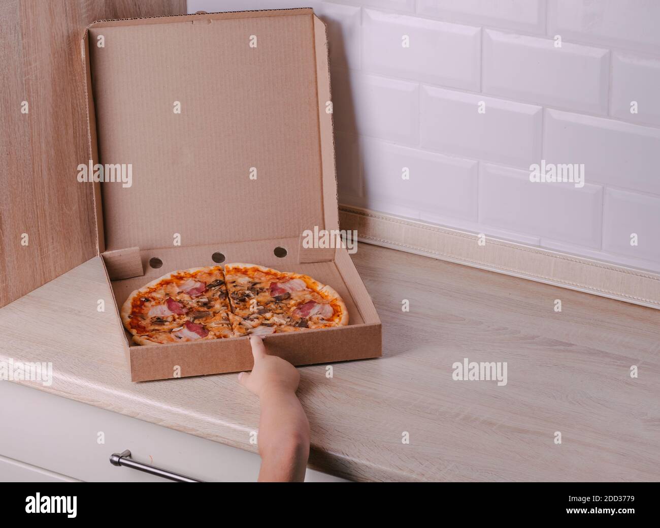 The child tries to steal a slice of pizza from the box. Food delivery ...