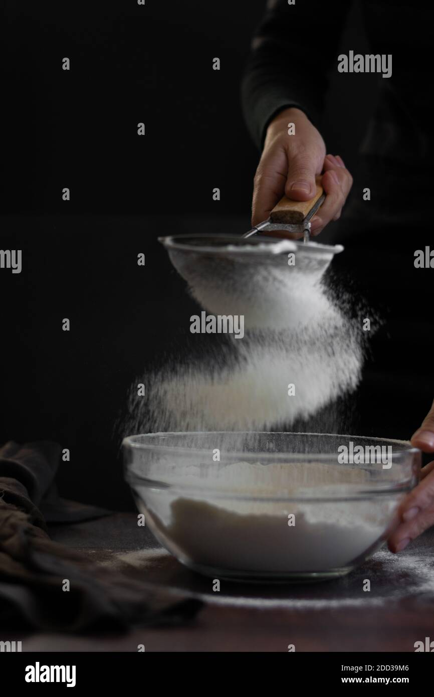 Crop view of woman hands sifting flour through sieve Stock Photo - Alamy
