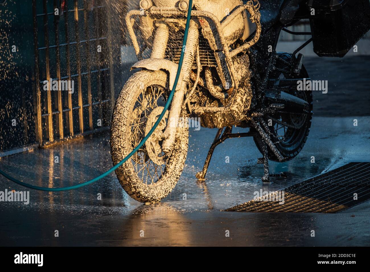 Motorbike washing series. Washing a motorcycle at a car wash at sunset ...