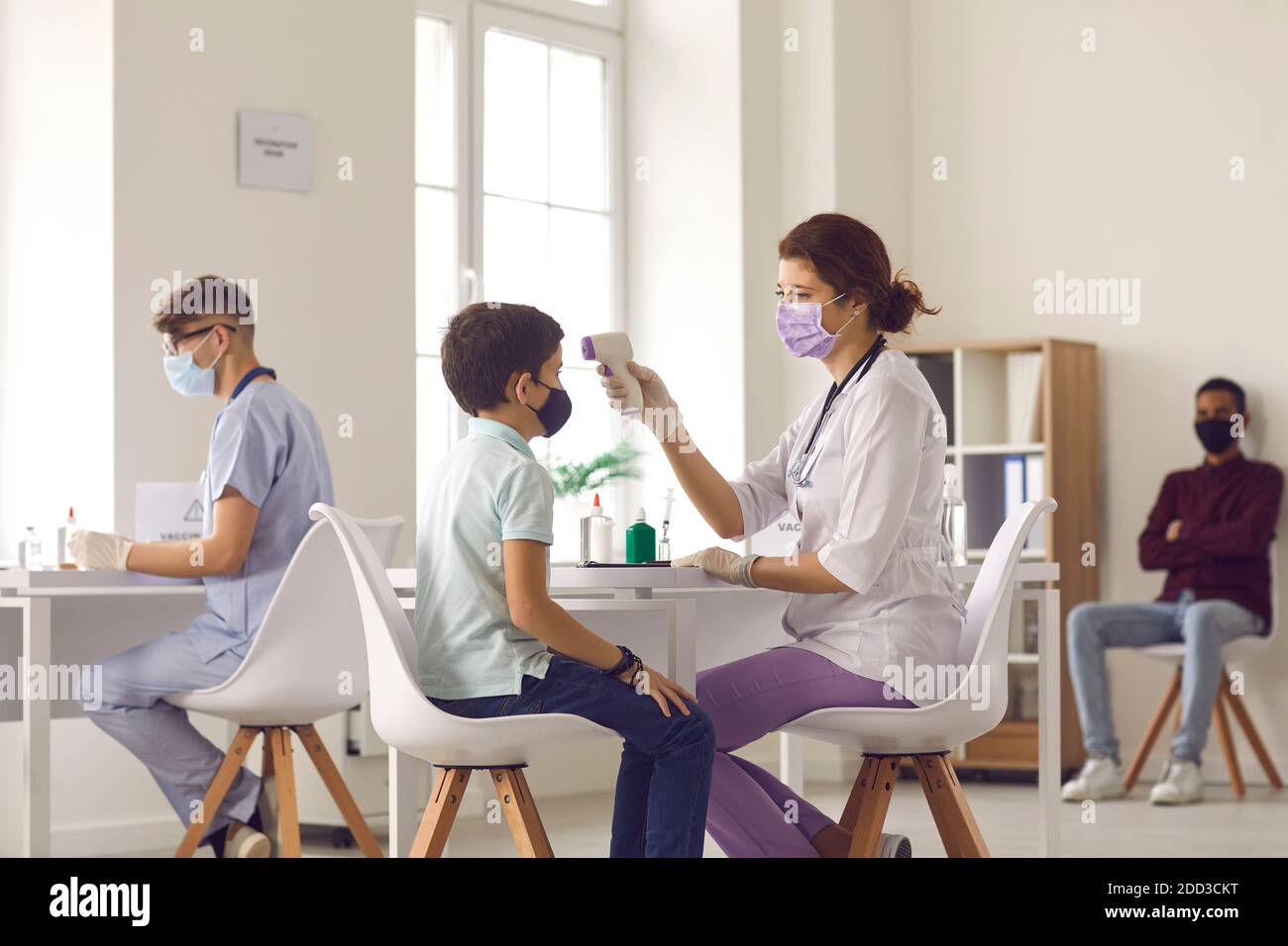 Nurse using non-contact infrared thermometer to measure little boy's ...