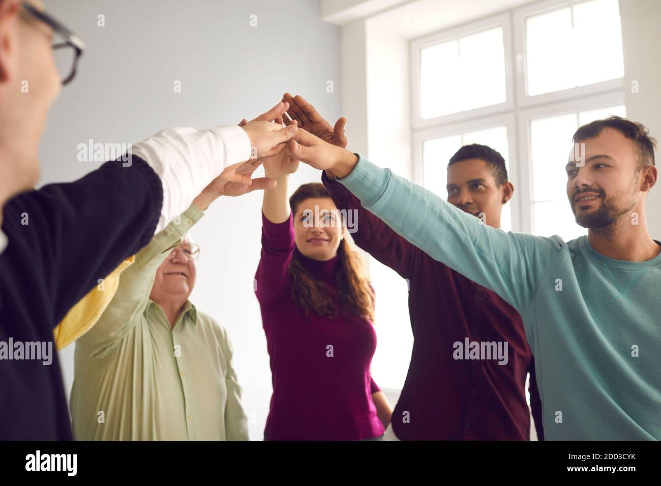 Team of happy diverse people joining hands during team building ...