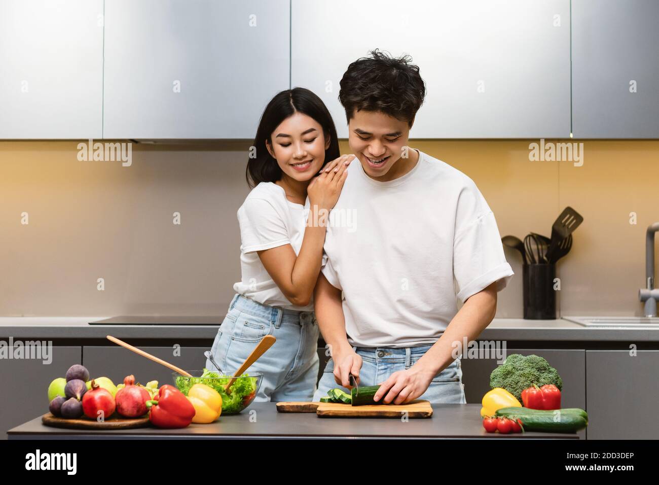 Loving Asian Wife Embracing Husband While Cooking Together In Kitchen ...