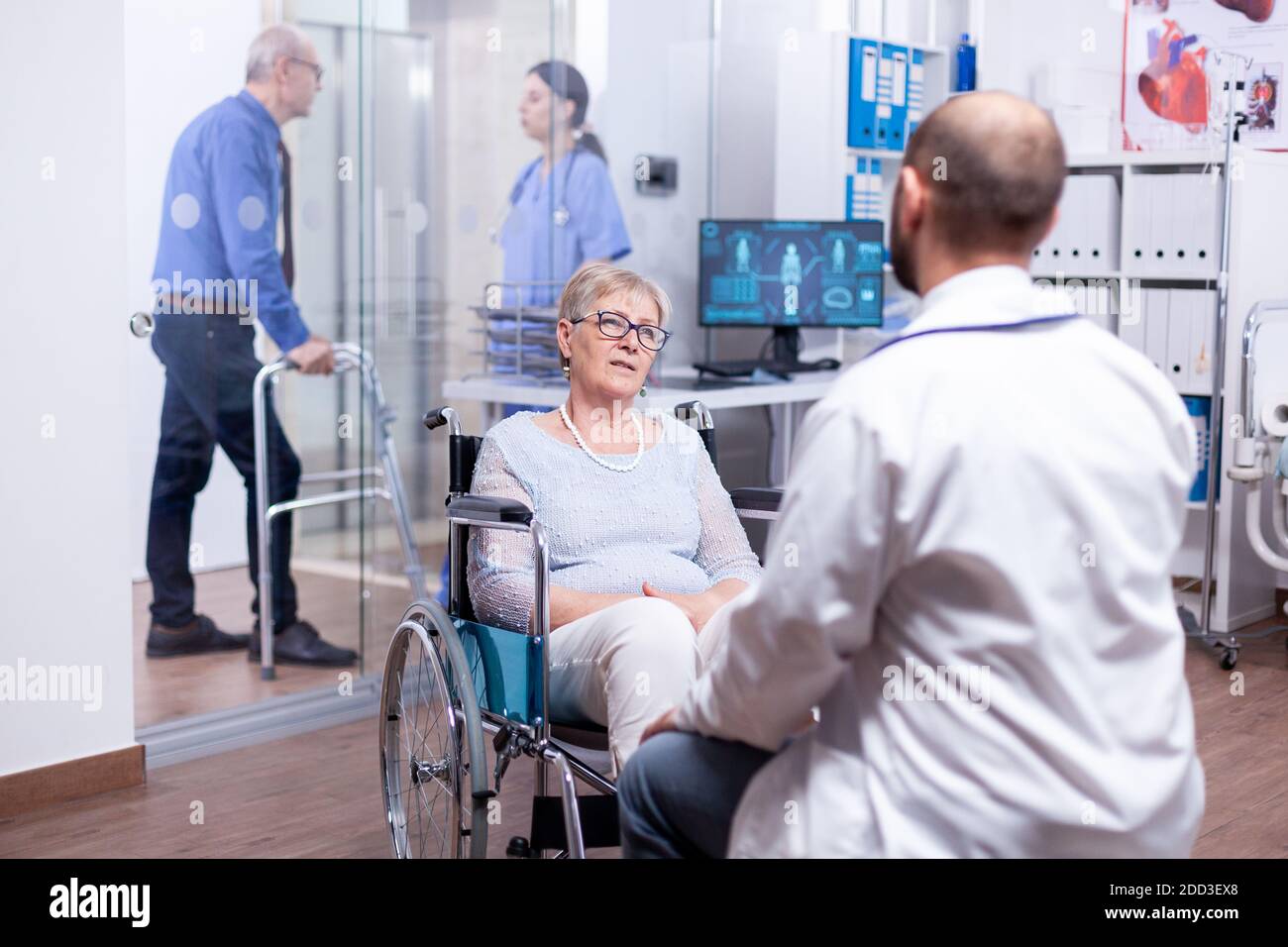 Giatrician consulting invalid woman in wheelchair in hospital ...
