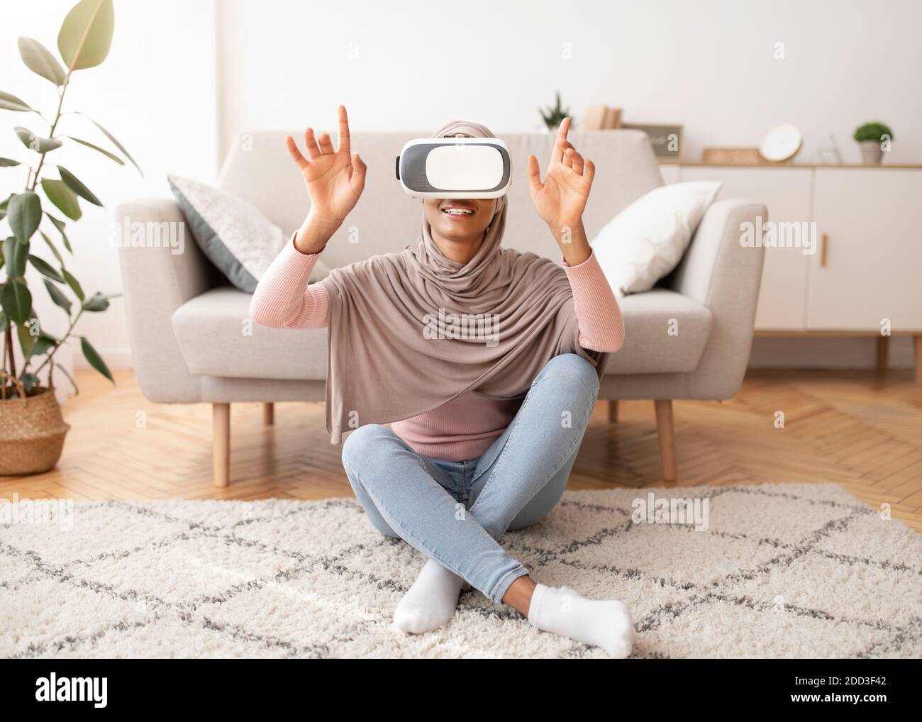 Weekend pastimes. Young Muslim woman in hijab interacting with virtual ...