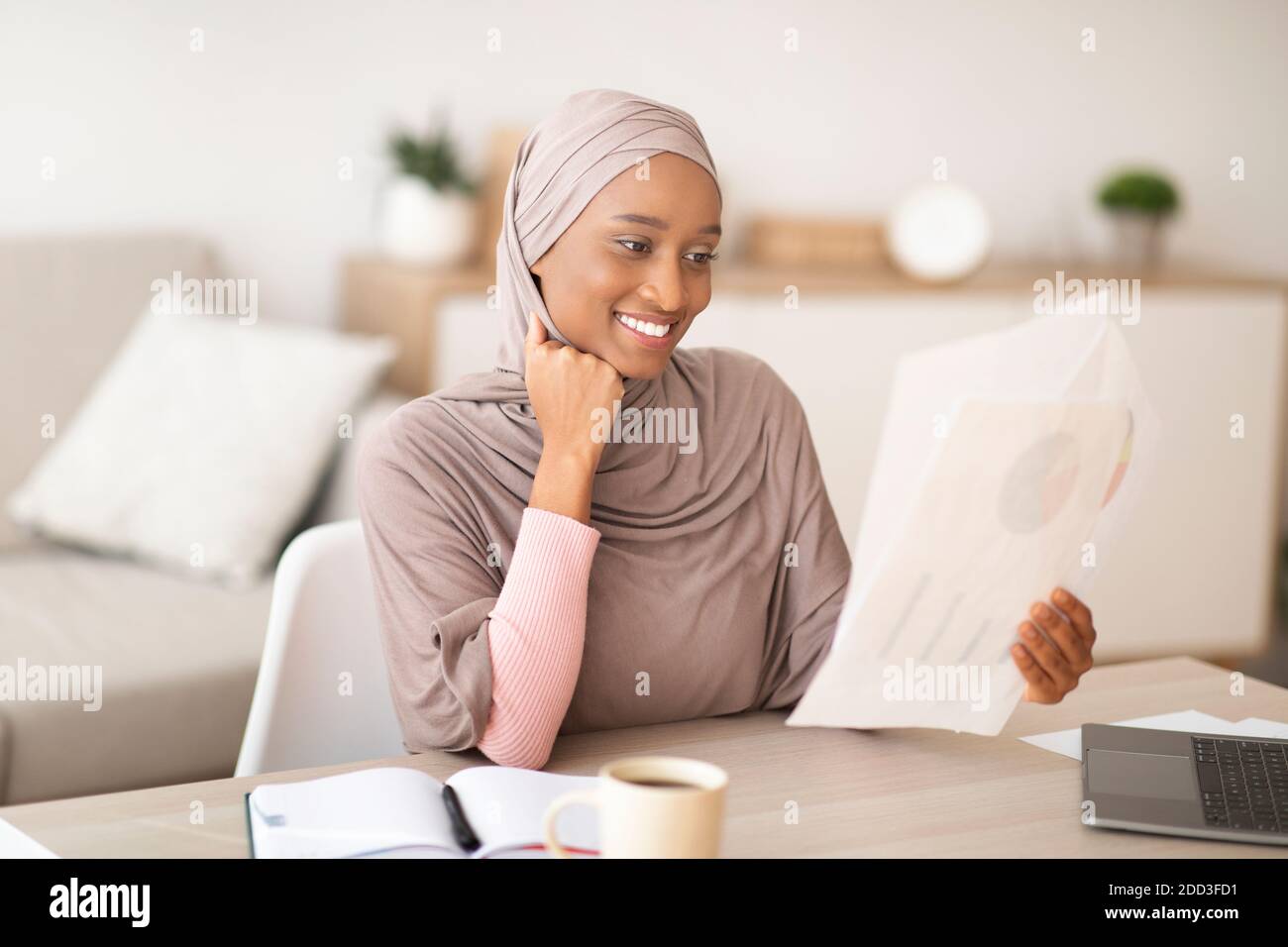 Remote work concept. Positive black Muslim lady in hijab studying ...