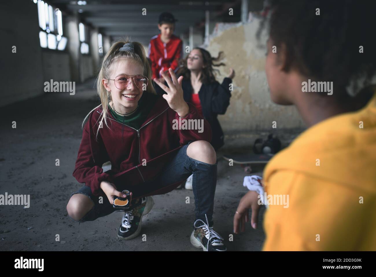 Group of teenagers gang sitting indoors in abandoned building, using ...