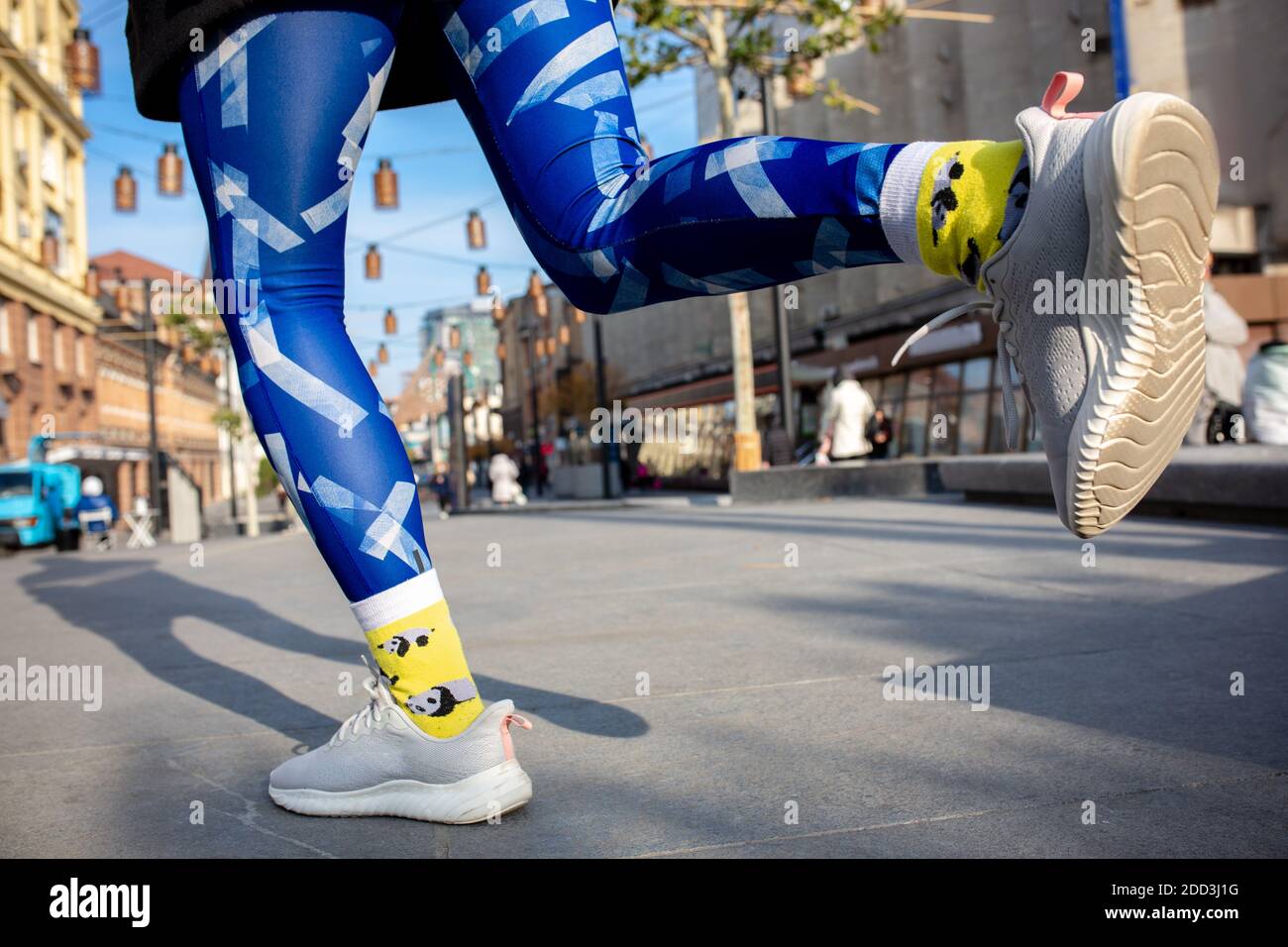 Close-up female legs in bright blue leggins and yellow socks running ...