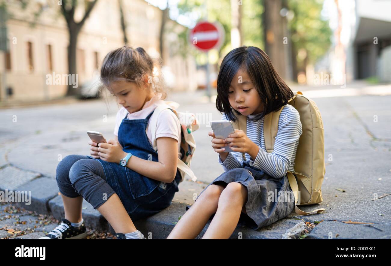 Small girls with smartphones outdoors in town, playing Stock Photo - Alamy