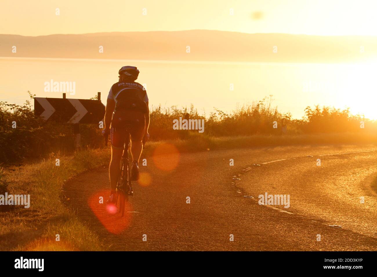Dunure, Ayrshire, A cyclist on curved road, cycles into a curve as a ...