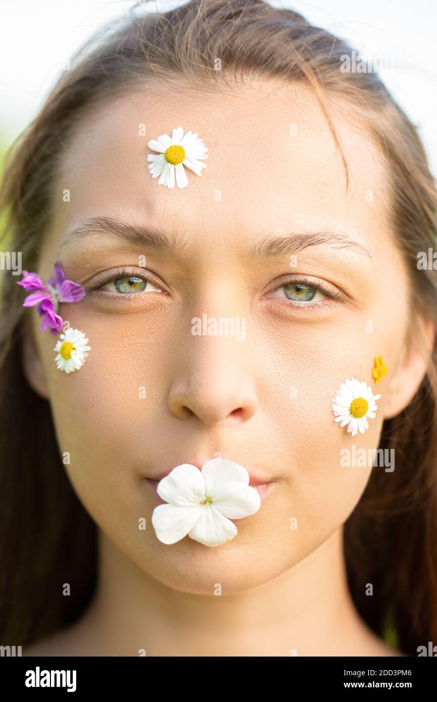 Close-up beautiful fresh face with wild flowers and daisy on forehead ...