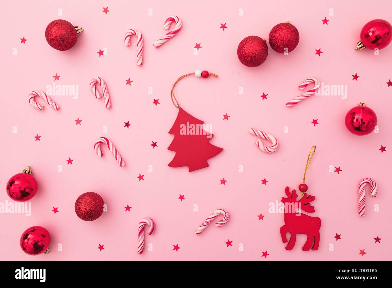New Year composition. Red toys, candy canes and confetti on pink. Flat ...