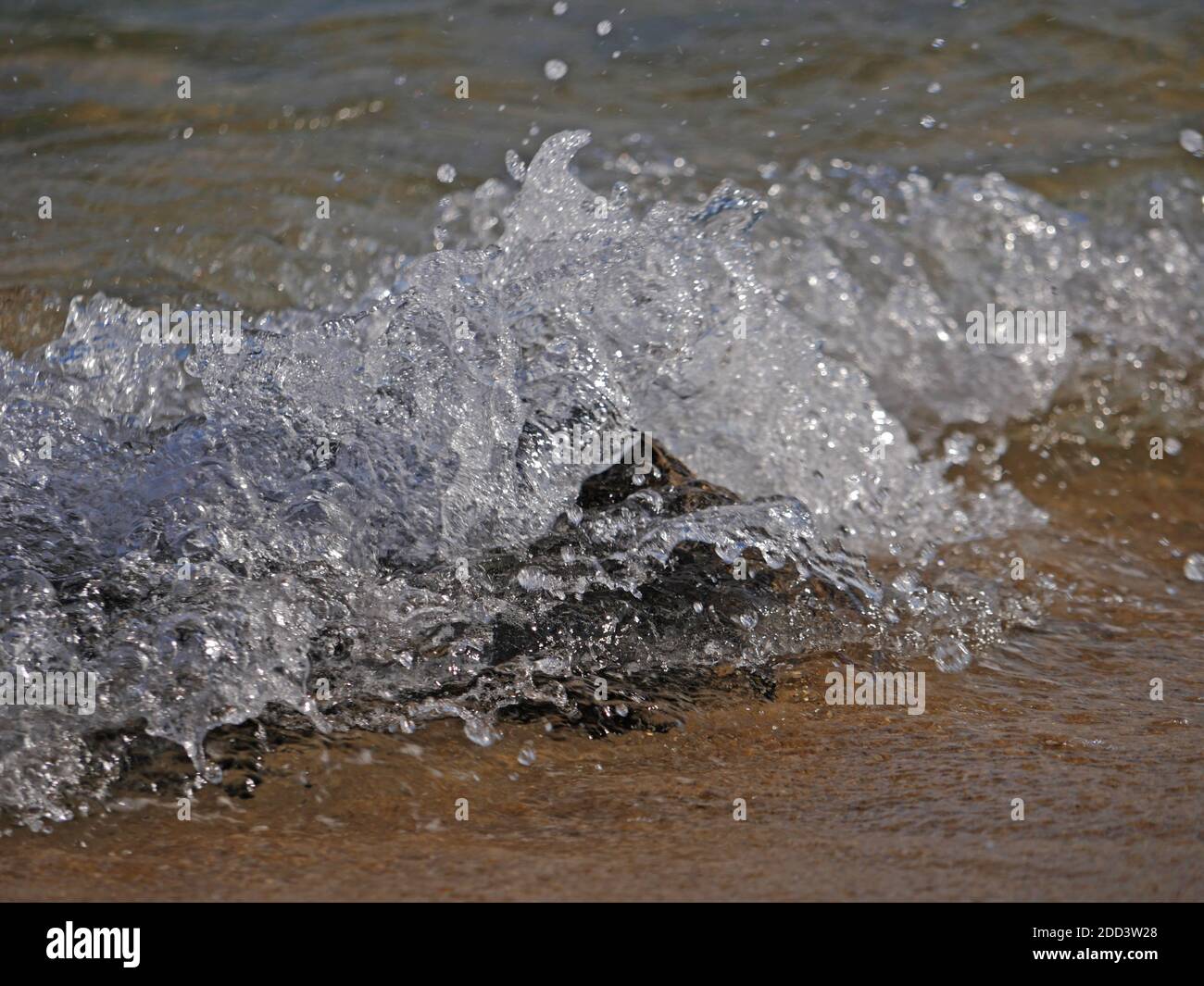 Closeup of a small wave breaking on a beach Stock Photo - Alamy