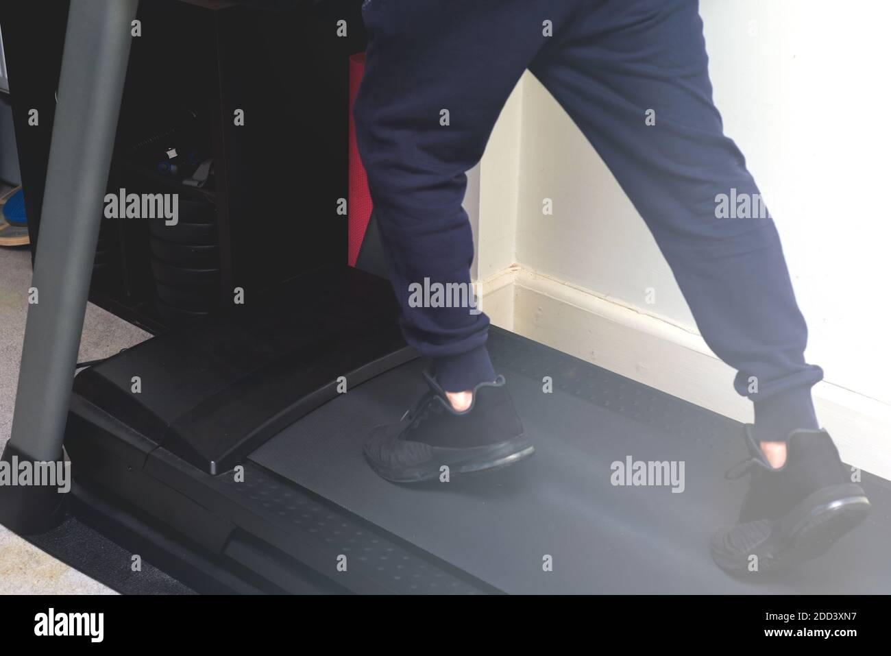 Man working out at home by running on a treadmill in converted gym room ...