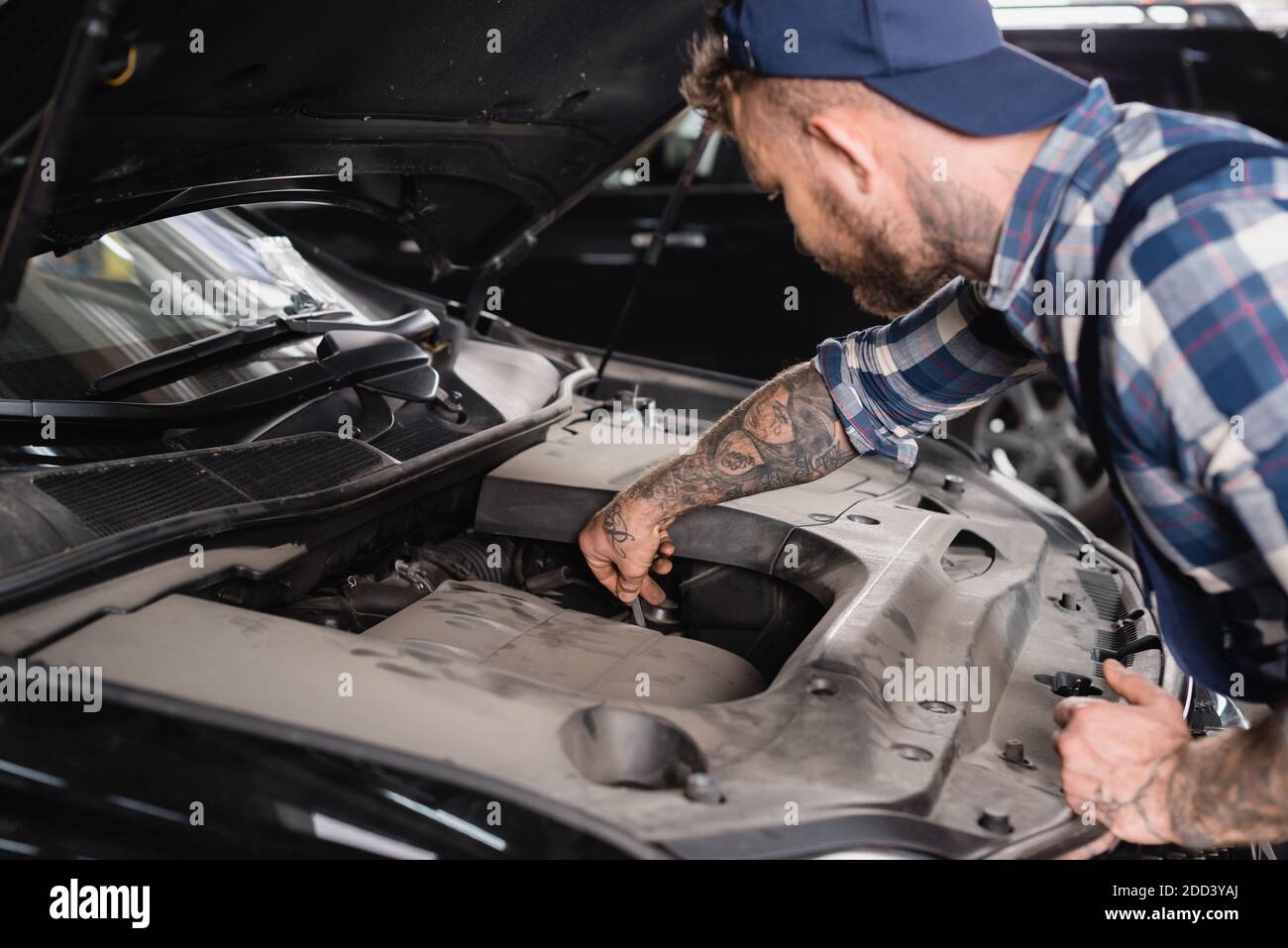 mechanic checking level of oil in car engine on blurred foreground ...