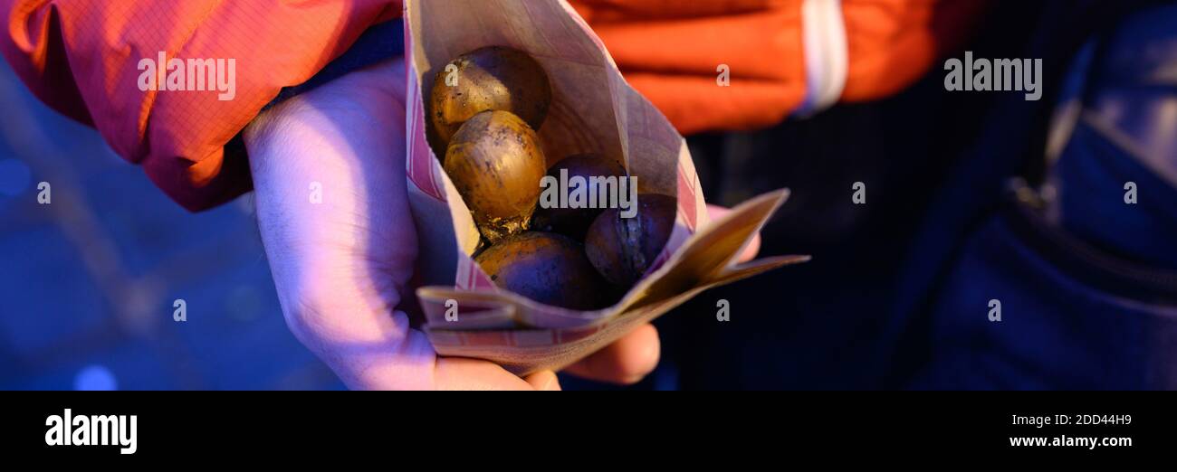 packaging of edible roasted red chestnuts in the hands of a man on the ...