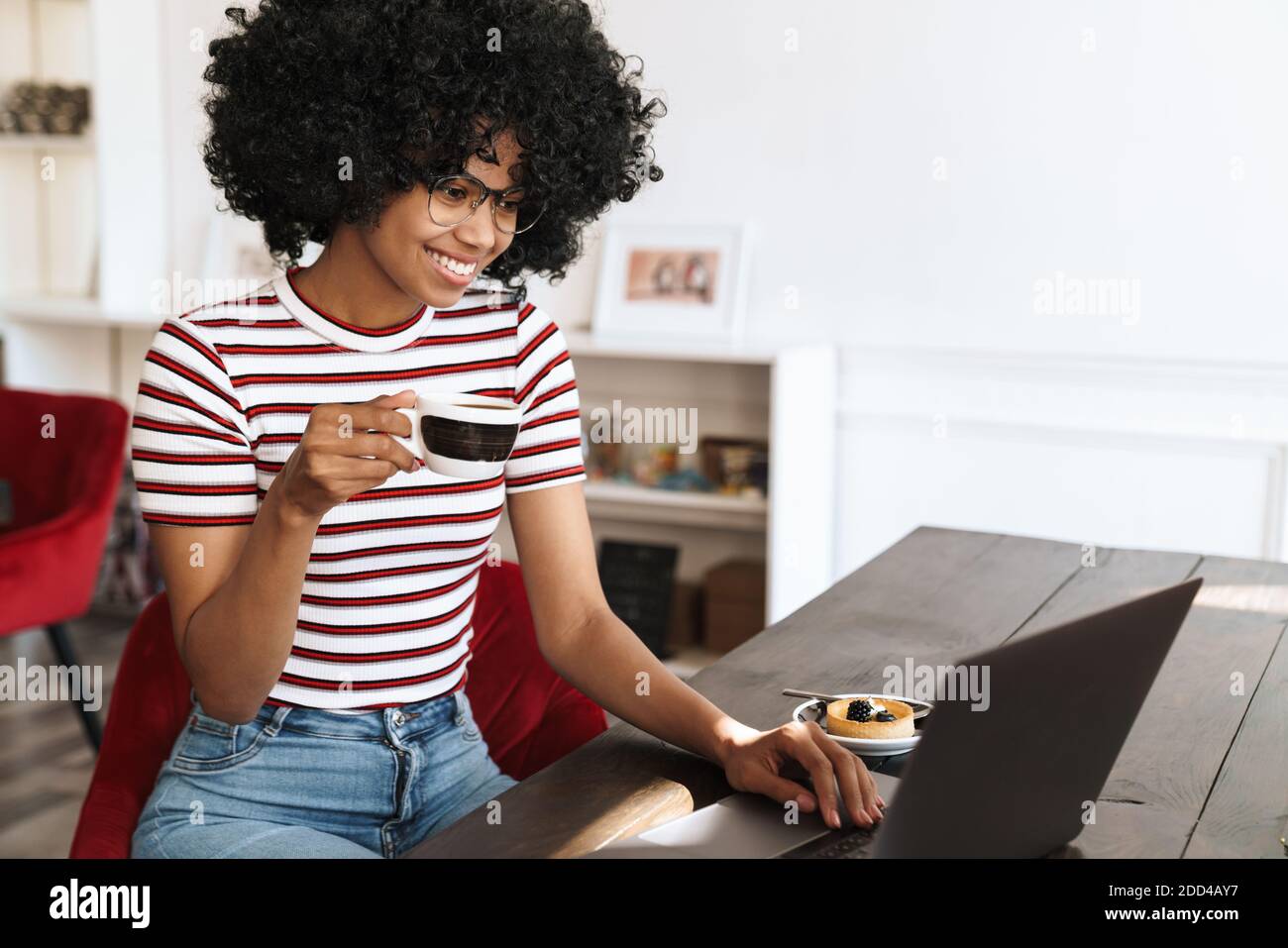 Smiling african american student girl doing homework with laptop while ...