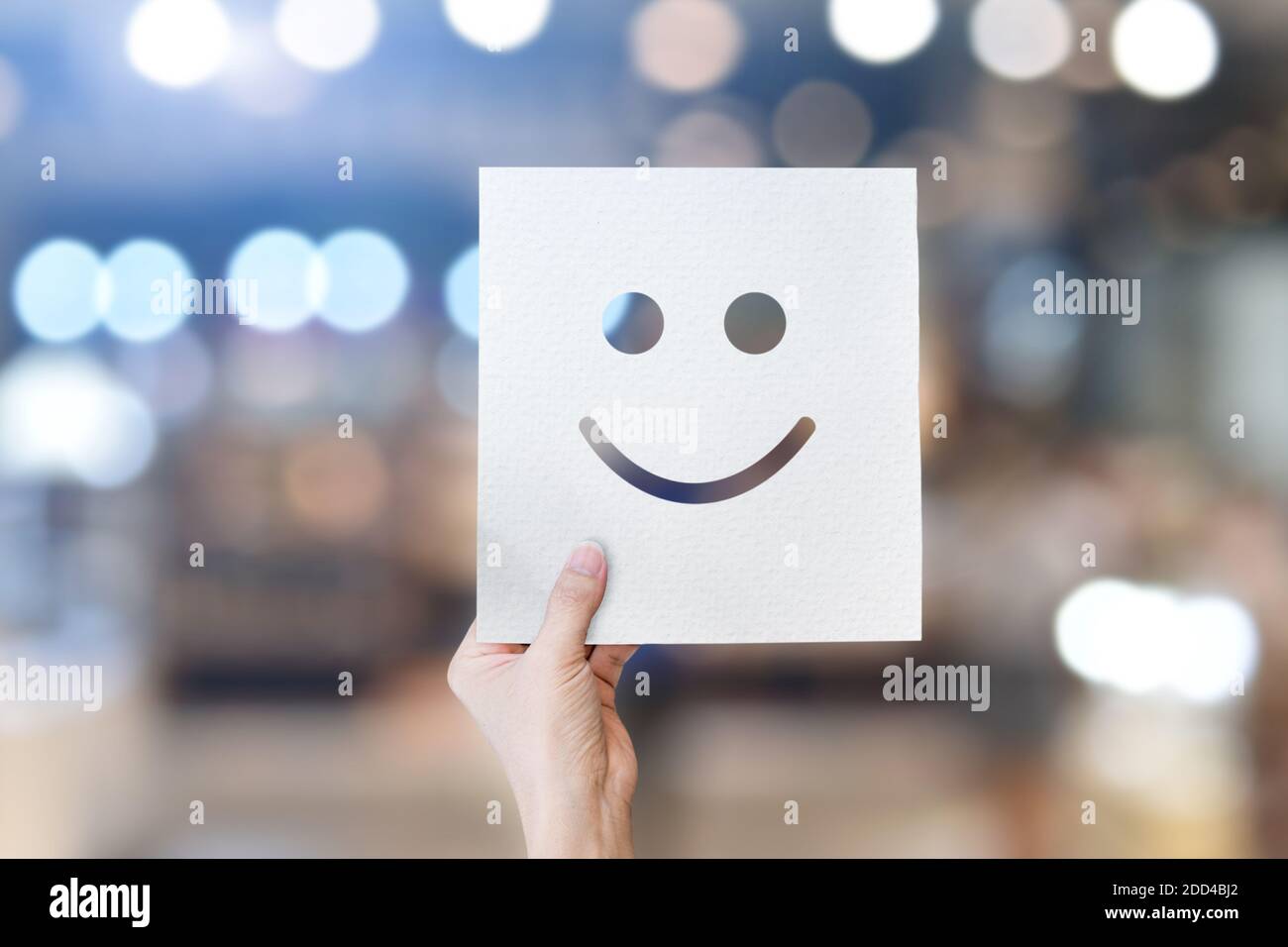 Hand holding white paper with smiley face emoticons (perforated paper ...