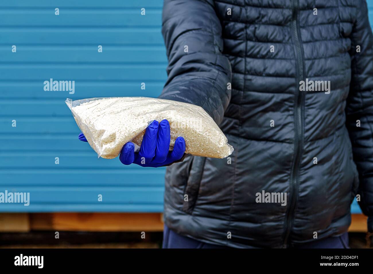 The girl passes rice at arm's length in a glove. Help during a pandemic ...