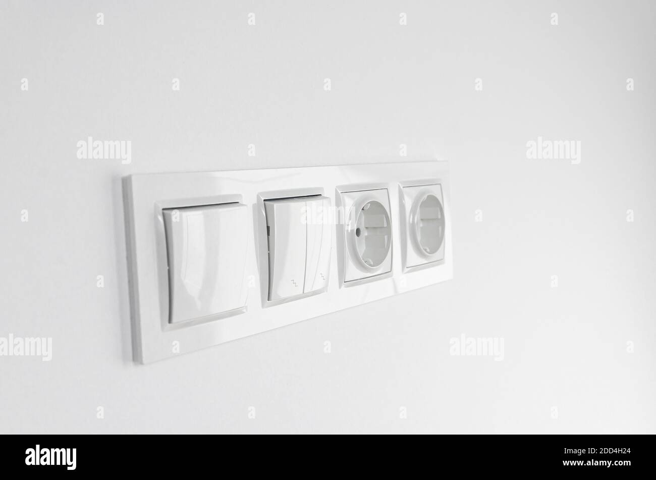 Blurred. White plastic walk-through switches and sockets on a white ...