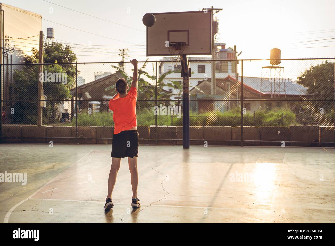 Caucasian young man playing basketball alone on urban track under ...