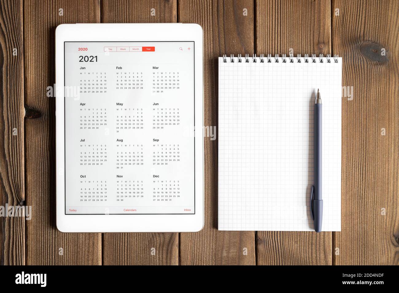 a tablet with an open calendar for 2021 year and a spring notebook with ...