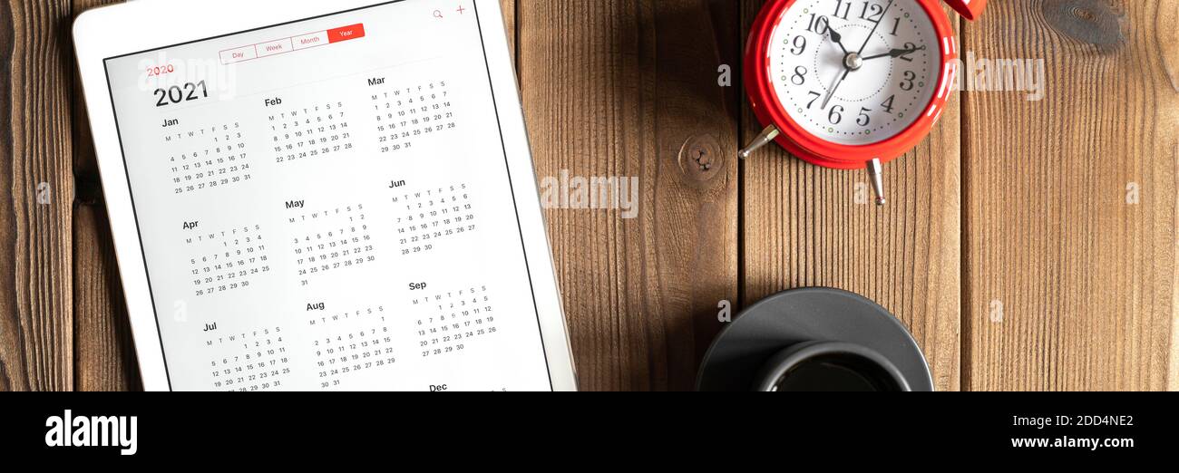 a tablet with an open calendar for 2021 year, a cup of coffee, and a ...