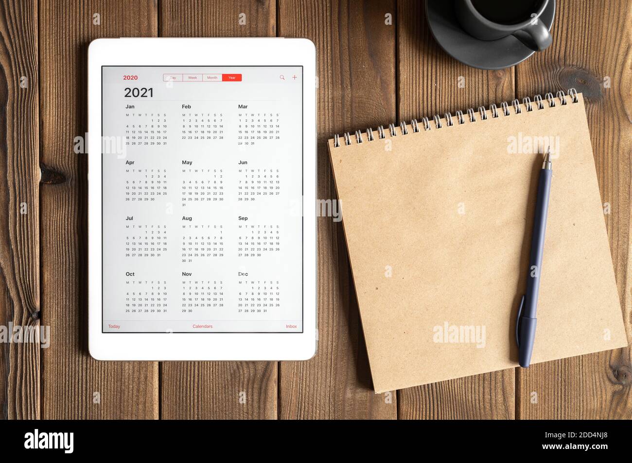 a tablet with an open calendar for 2021 year, a cup of coffee and a ...