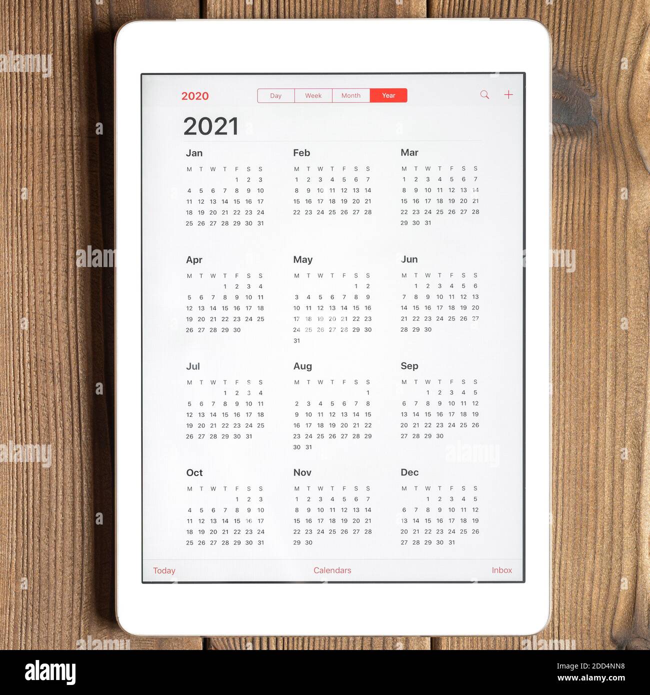 a tablet with an open calendar for 2021 year on a wooden boards table ...