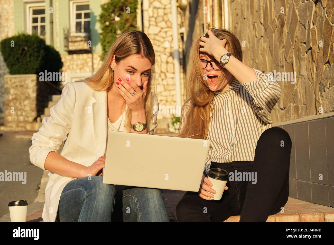 Two young beautiful women having fun looking into the laptop monitor ...