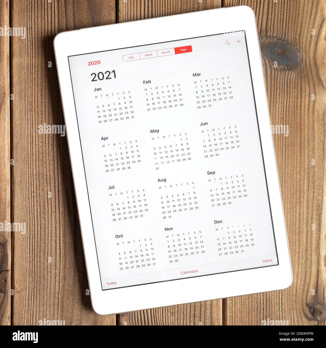 a tablet with an open calendar for 2021 year on a wooden boards table ...