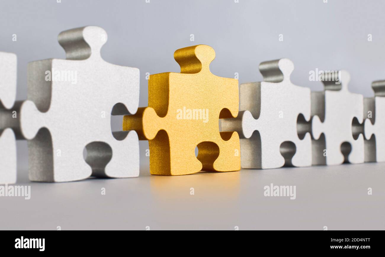 Silver puzzle pieces in a row, one gold Stock Photo - Alamy