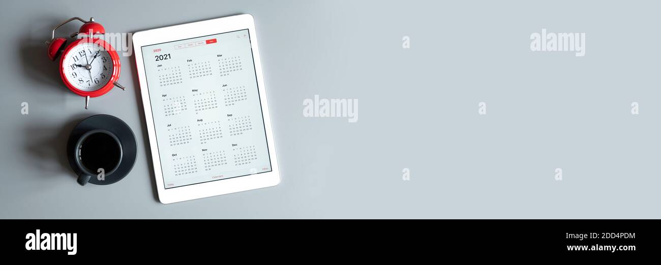 a tablet with an open calendar for 2021 year, a cup of coffee, and a ...