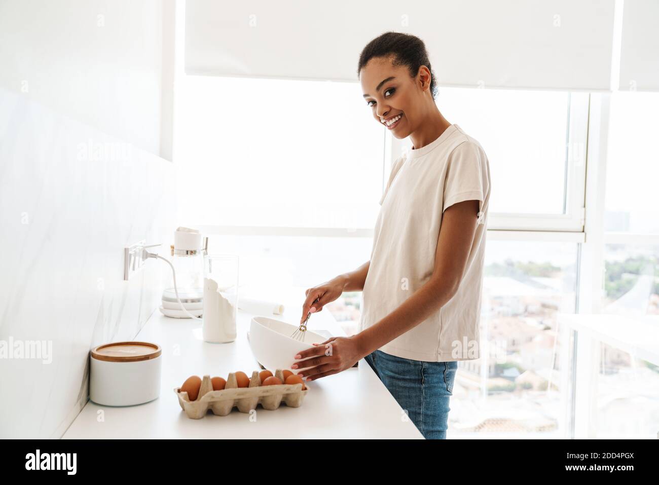 Image of a young happy african woman cooking at the kitchen at home ...