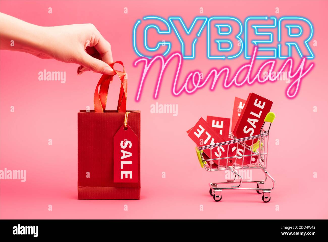 cropped view of woman holding small shopping bag near cart with sale ...