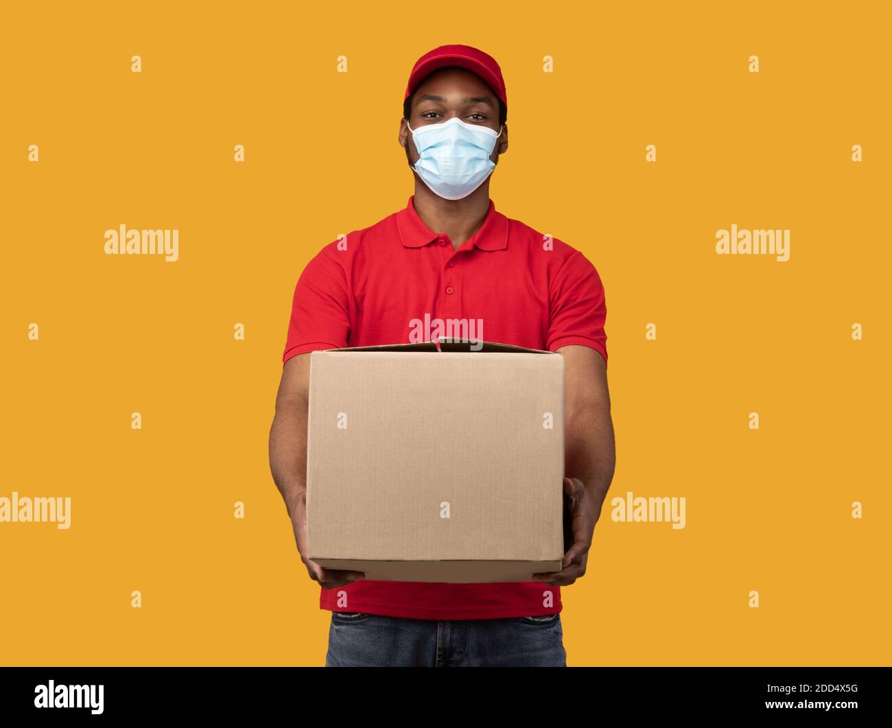 Black delivery man in medical mask giving box Stock Photo - Alamy