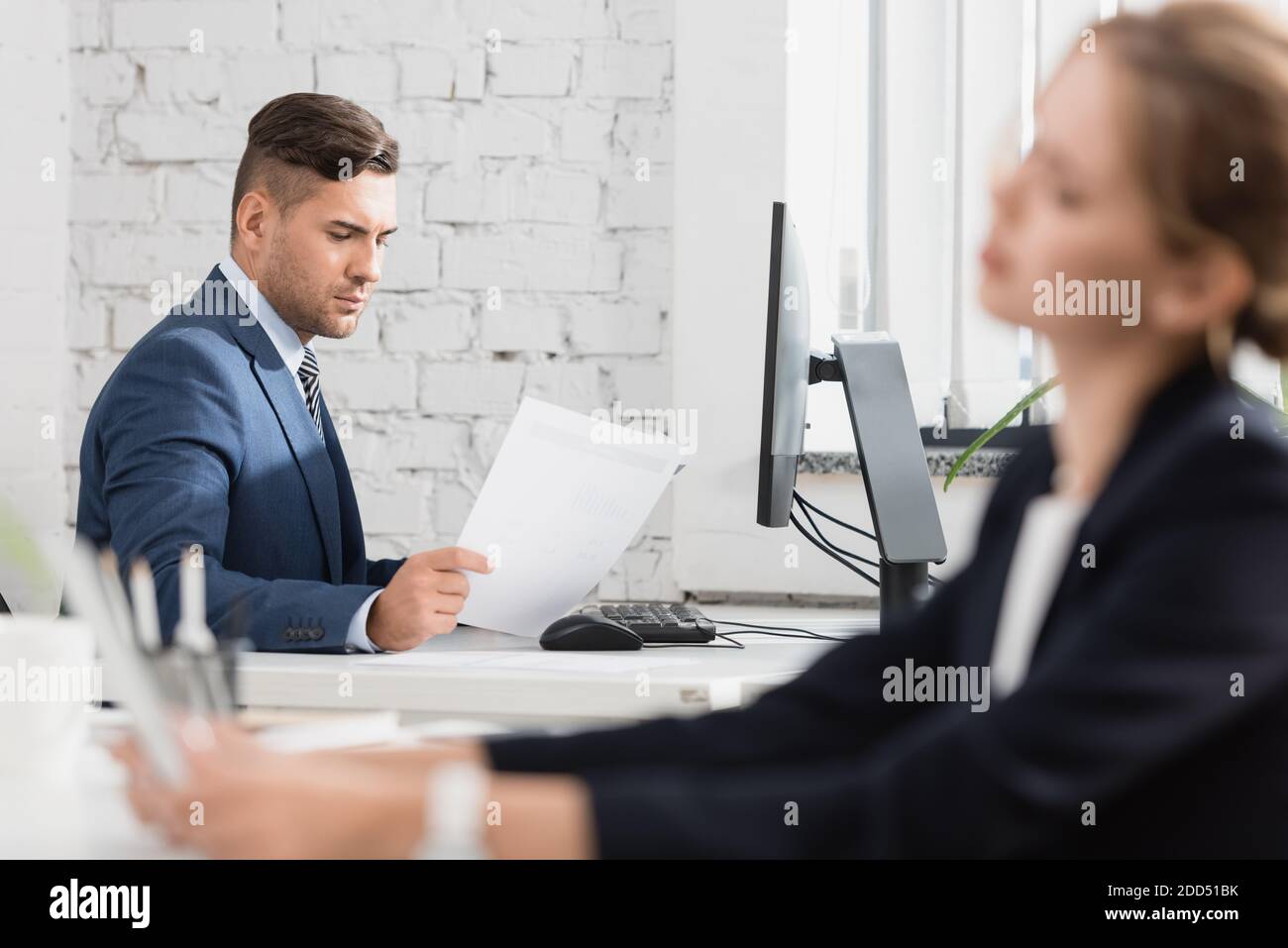 Focused businessman looking at paper sheet, while sitting at table on ...